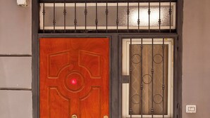 Uma porta de madeira com um emblema circular, um portão de metal e uma pequena janela com parede texturizada.
