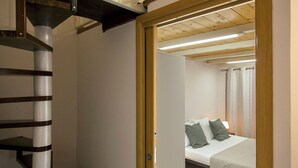 Um quarto com cama, teto de madeira e escada.