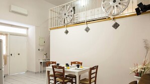 Uma área de refeições com uma mesa branca, quatro cadeiras de madeira e um ventilador de teto.