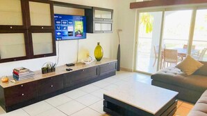 Uma sala de estar moderna com um móvel de entretenimento em madeira escura, uma televisão de tela plana, um sofá e uma mesa de centro.