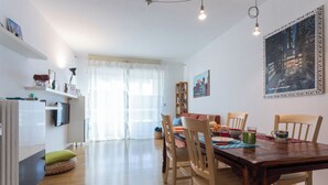 Uma sala de jantar moderna com uma mesa de madeira, cadeiras e uma televisão na parede.