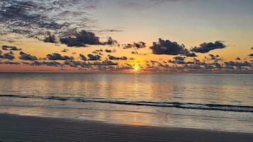 Um pôr do sol sobre um mar calmo, com céu claro e nuvens.