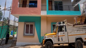 Edifício em construção com vários andares e um caminhão estacionado na frente.
