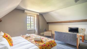 Quarto de hotel com cama, escrivaninha com televisão e janela.