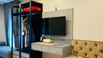 Uma sala de estar moderna com sofá, televisão na parede, guarda-roupa embutido e uma mesinha com bandeja.