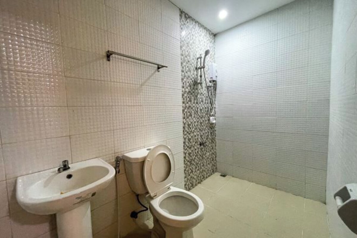 Casa de banho com sanita, lavatório e chuveiro.