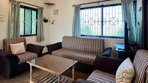 Uma sala de estar com sofás listrados, uma mesa de centro de madeira e uma televisão em um suporte.
