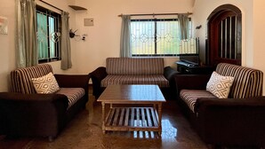 Uma sala de estar com sofás listrados, uma mesa de centro de madeira e um ventilador de teto.