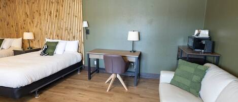 Quarto de hotel com cama, escrivaninha, cadeira e sofá.