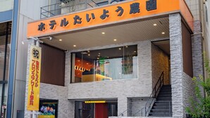 Um hotel com fachada moderna, entrada visível e uma placa indicando que é um hotel.