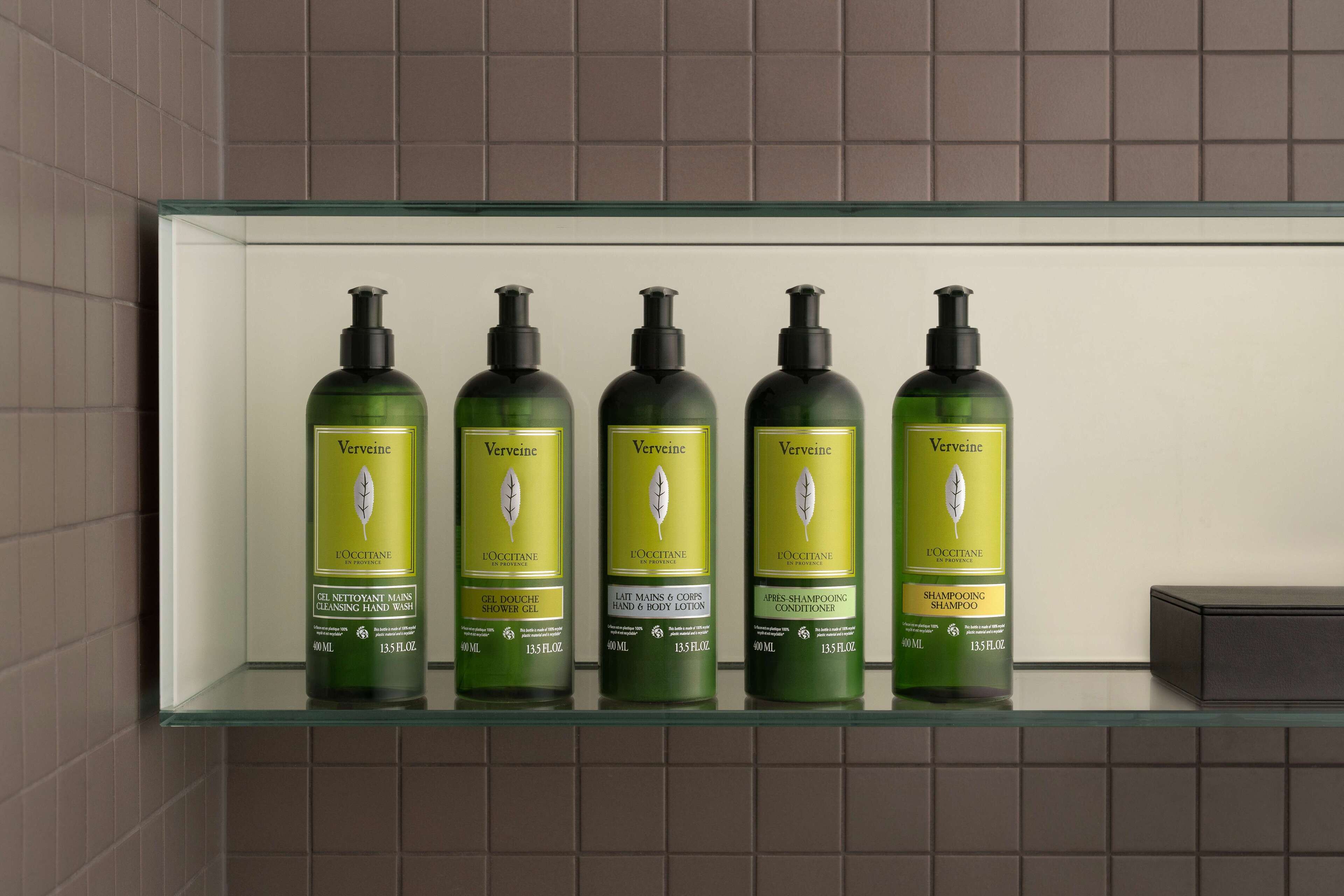 Uma prateleira no banheiro com cinco frascos de produtos de banho Verveine.