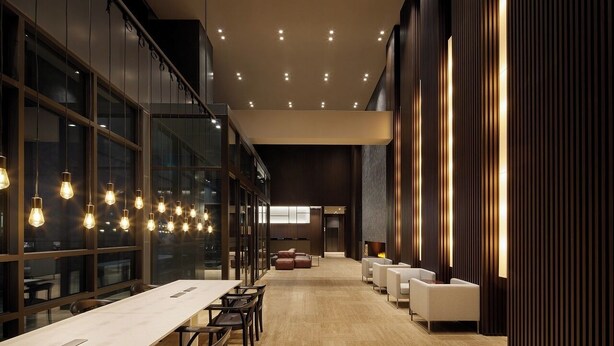 Um interior moderno com uma mesa comprida, área de estar e grandes janelas.