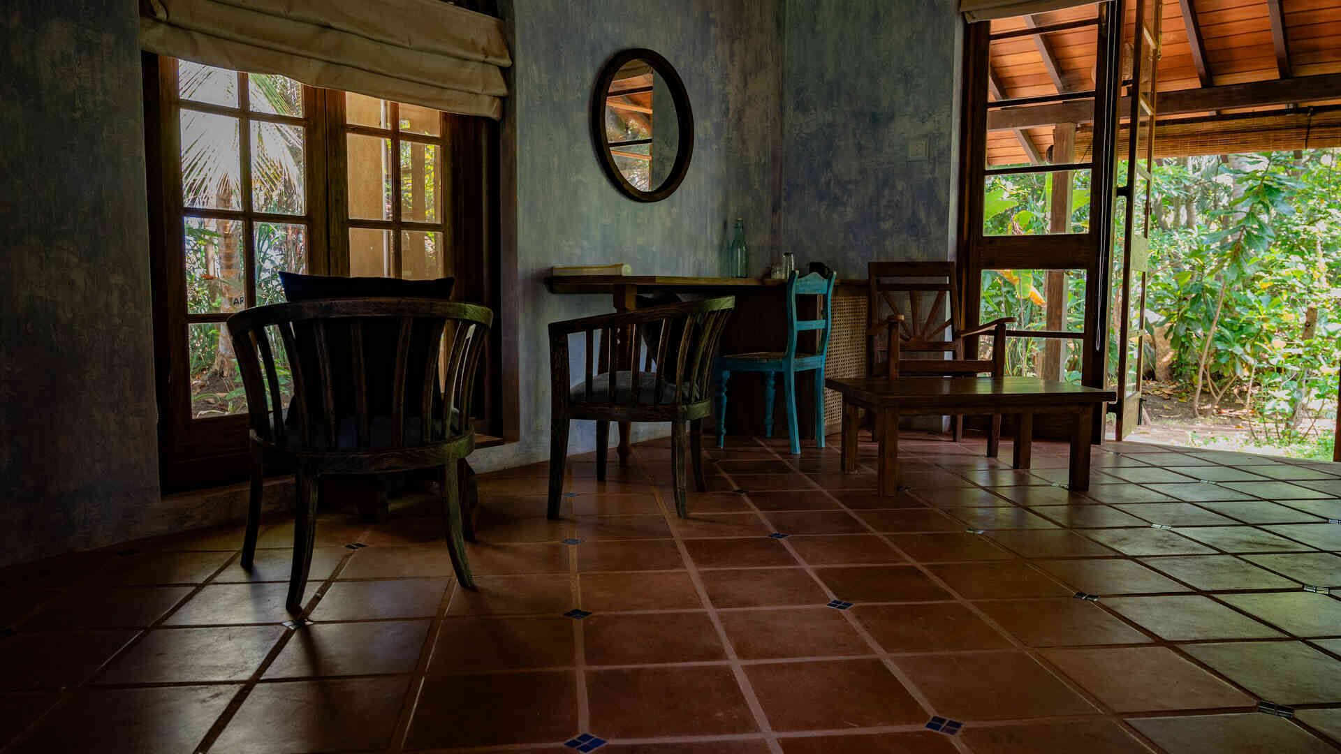 Quarto com soalho em azulejos, uma mesa de madeira e várias cadeiras.