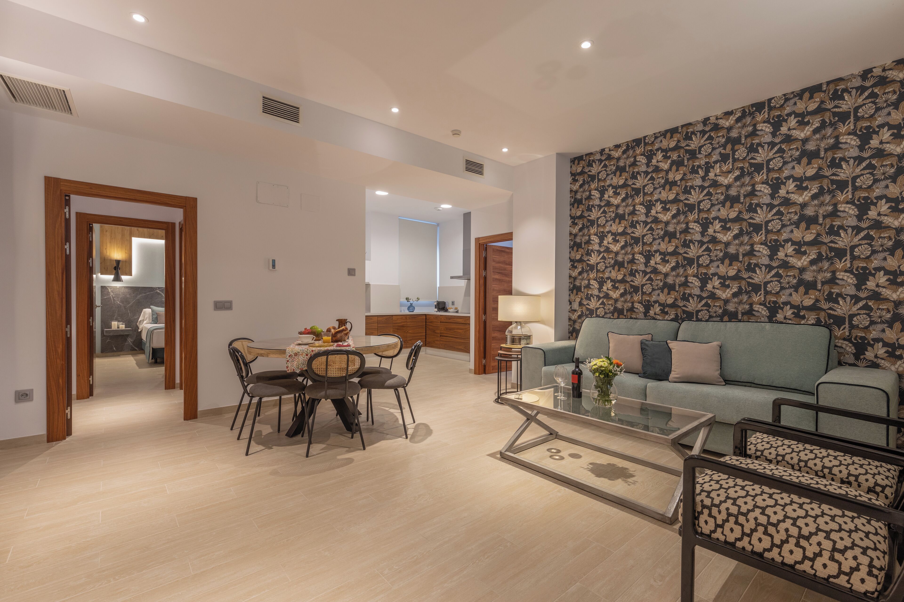 Uma sala de estar moderna com um sofá, uma mesa de jantar com cadeiras e uma parede estampada.