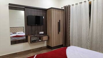 Quarto de hotel com cama, televisão na parede, guarda-roupa e cortina.