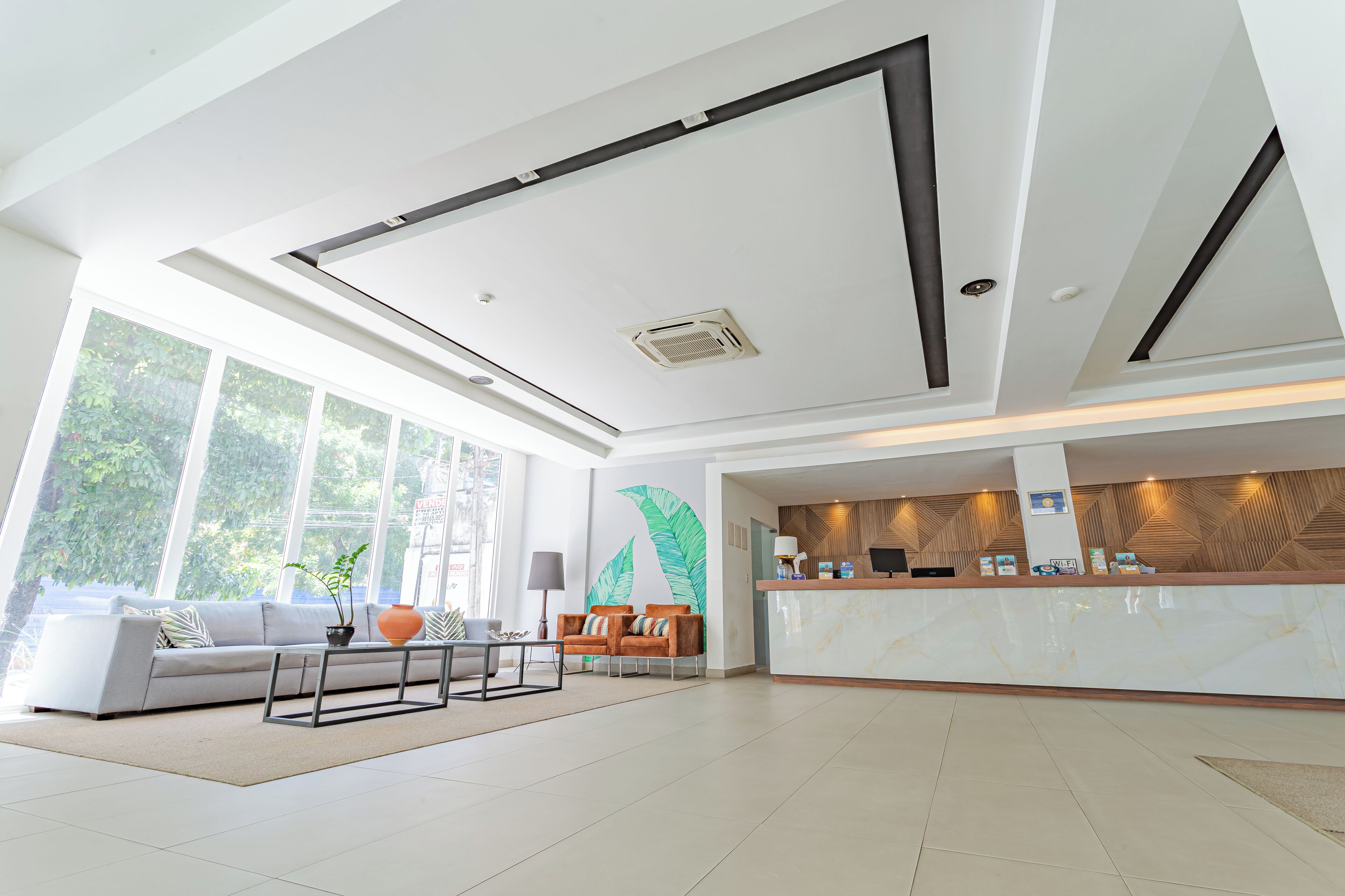 Um hall amplo com balcão de recepção, área de estar e grandes janelas.