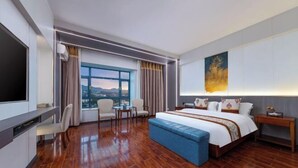 Quarto de hotel moderno com uma cama grande, uma TV, uma escrivaninha e vista para a cidade.