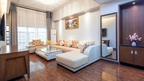 Uma sala de estar moderna com um sofá seccional, uma mesa de centro de vidro e um armário de madeira.