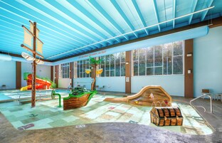 Piscina interior com toboáguas, área de recreação com tema náutico e um barco de madeira.