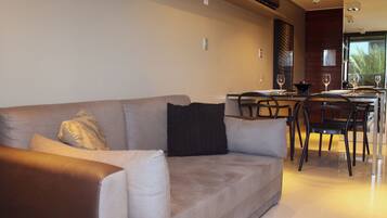 Uma sala de estar moderna com sofá, mesa de jantar, cadeiras e janela com vista.