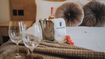 Uma cama com uma garrafa de vinho, um copo e uma toalha com a inscrição 'Jules & Laurent'.