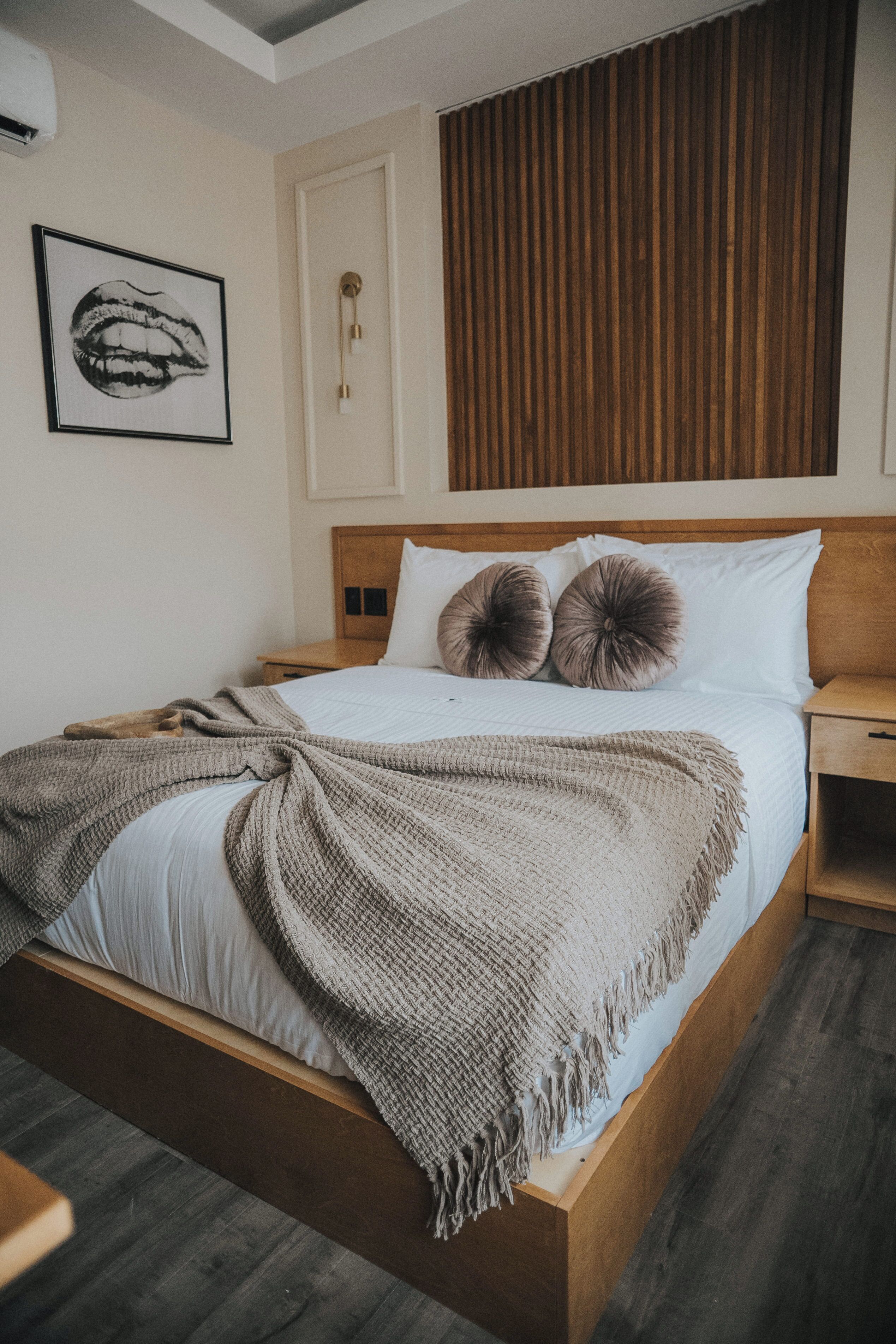 Uma cama bem arrumada com cabeceira de madeira, um travesseiro grande e um cobertor.