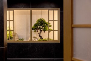 Uma janela com um bonsai, pedras e musgo.