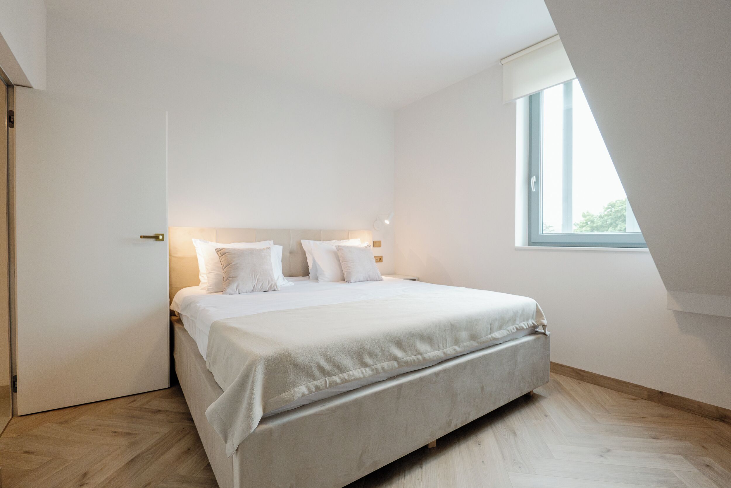 Quarto com uma cama grande, janela e porta.