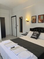 Quarto de hotel com cama, mesa de cabeceira, espelho e obras de arte na parede.