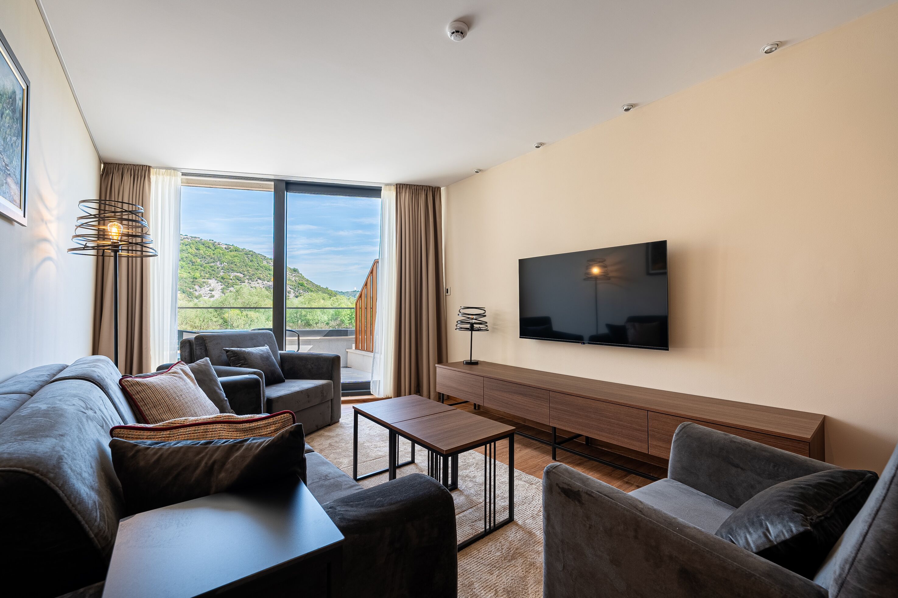 Uma sala de estar moderna com sofá, poltronas, mesa de centro e televisão fixada na parede.