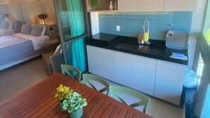 Quarto de hotel compacto com cozinha compacta, área de refeições com mesa e cadeiras, e cama com vista.