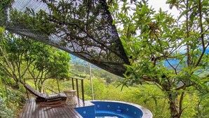 Uma banheira de hidromassagem rodeada por um deck de madeira, com um caminho de tijolos que a leva até ela.