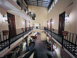 Um átrio espaçoso e bem iluminado com um pátio central, teto duplo e várias varandas com grades.