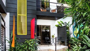 Uma casa moderna de dois andares com varanda, área de estar externa e vegetação exuberante.
