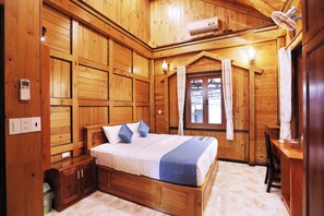 Quarto de madeira com cama, escrivaninha e janela com cortinas.