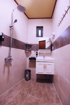 Casa de banho com chuveiro, pia e sanita.