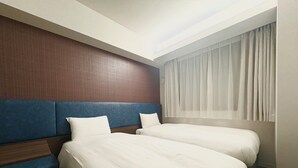 Quarto de hotel com duas camas, uma cabeceira de madeira e uma janela com cortinas.