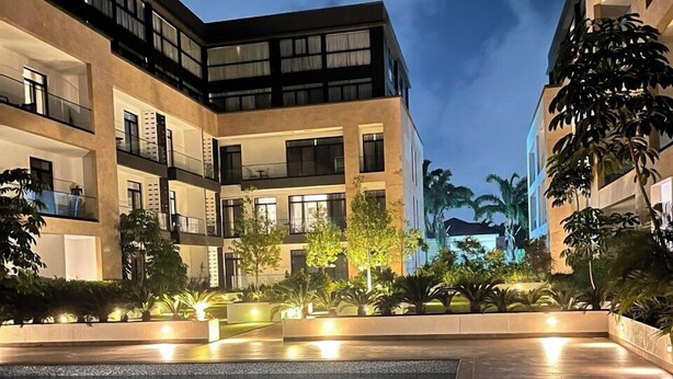 Um edifício moderno com várias varandas e uma piscina em primeiro plano.