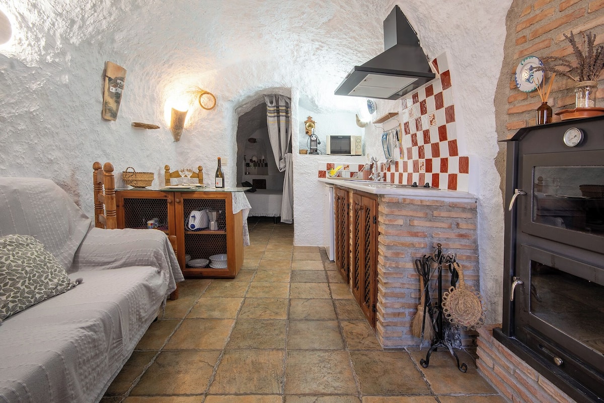 Um interior aconchegante com piso de pedra, cozinha com forno de tijolos e área de jantar com azulejos xadrez.