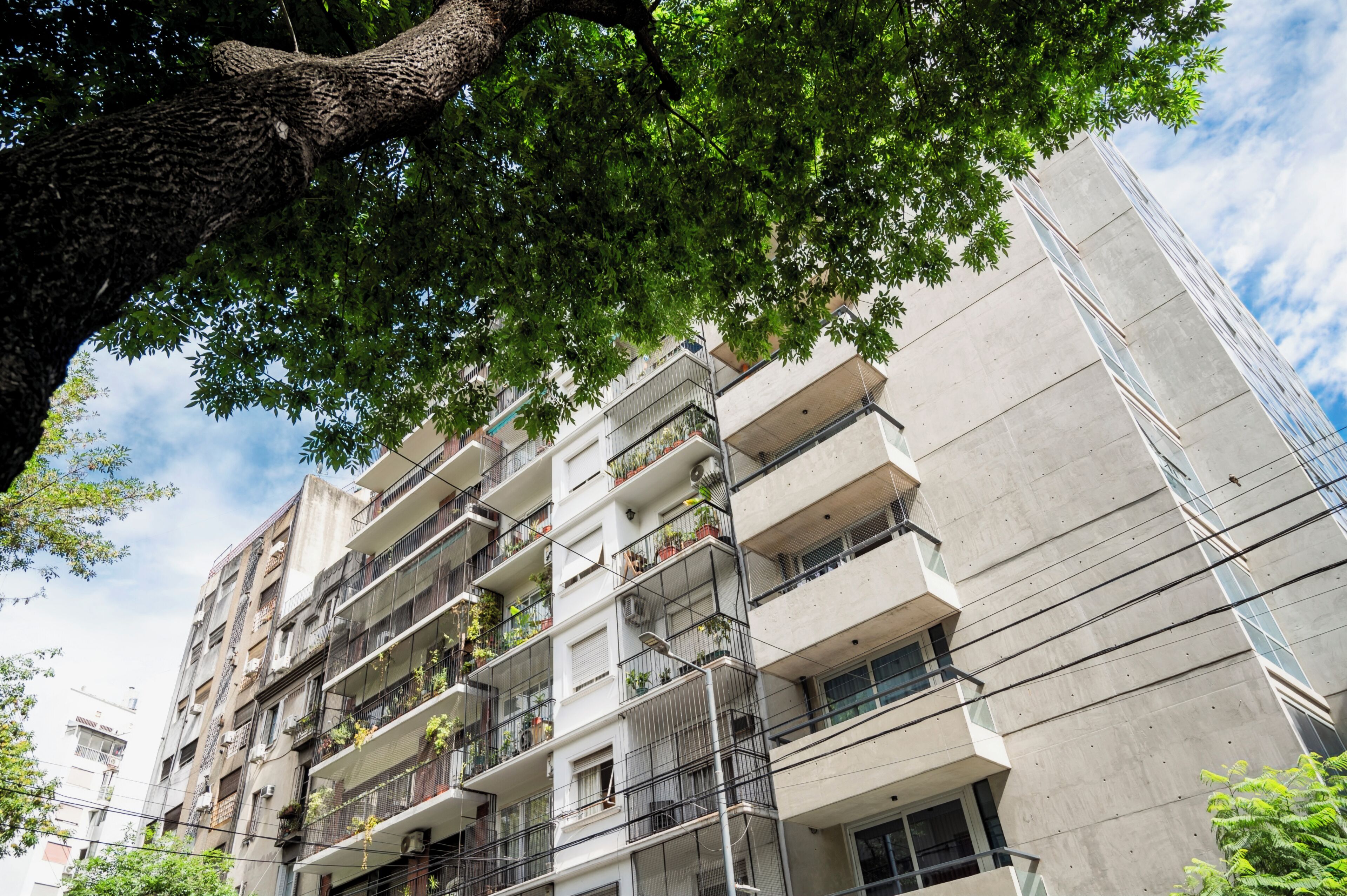 Um edifício residencial de vários andares com varandas, algumas com plantas.