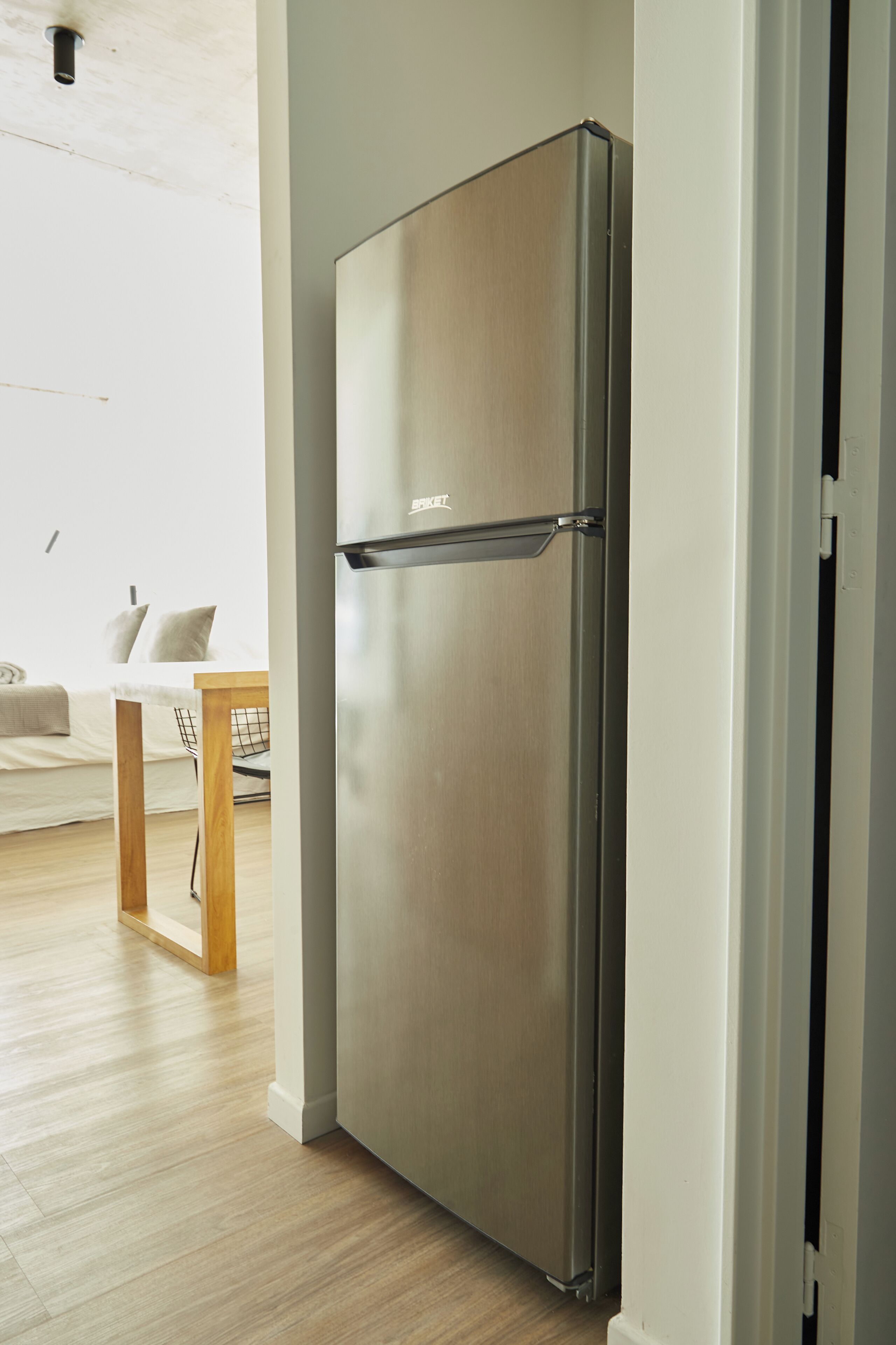 Uma cozinha moderna com geladeira de aço inoxidável, piso de madeira e design minimalista.