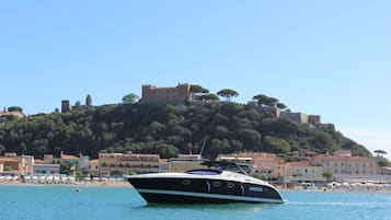 Um iate em um mar calmo, com um castelo histórico ao fundo, numa colina.