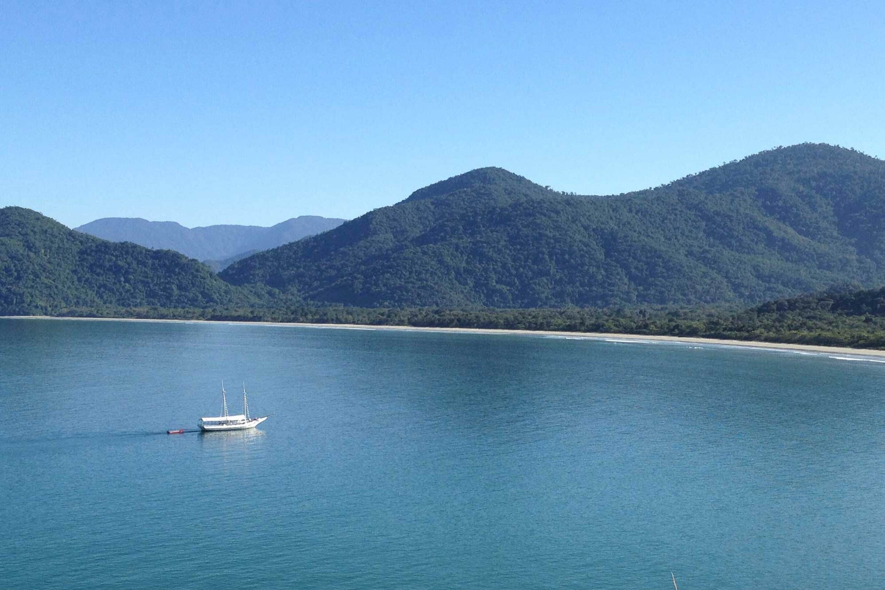 Um barco em um mar calmo, com montanhas ao fundo.