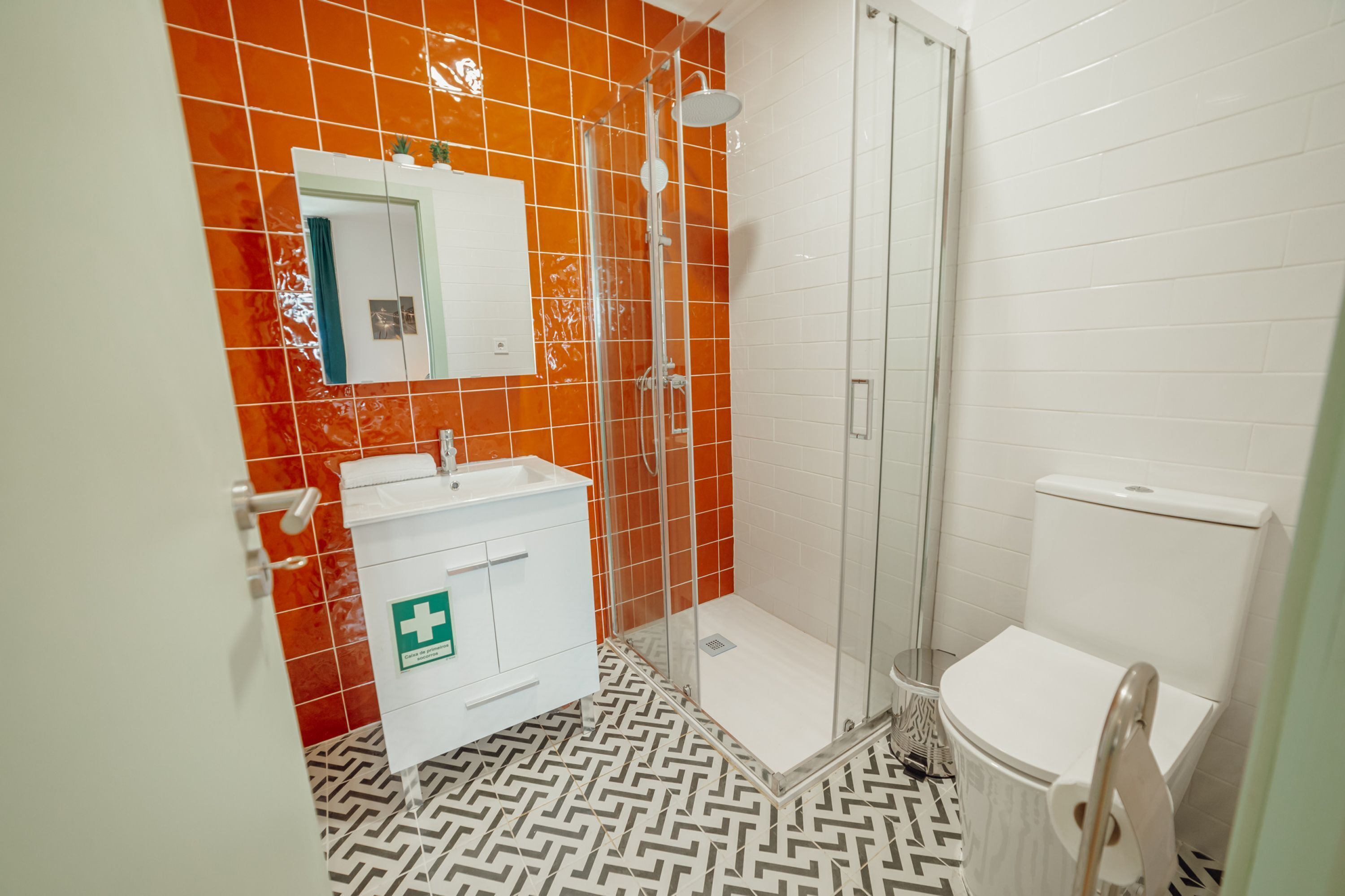 A bathroom with a shower, toilet, sink, and mirror.