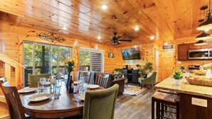 Interior de cabana de madeira com sala de jantar, sala de estar e cozinha.