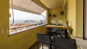 Uma varanda com mesa, cadeiras e vista para a cidade.
