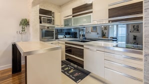 Uma cozinha moderna com eletrodomésticos embutidos, uma ilha central e uma parede de proteção com painéis de madeira.