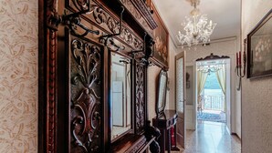 Um corredor ornamentado com painel de madeira, um candelabro e vista para uma varanda externa.