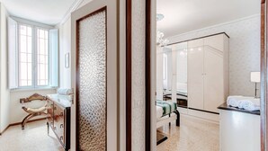 Quarto de hotel com cama grande, área de estar com poltrona e mesinha, guarda-roupa e banheiro com espelho e pia.