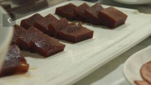 Uma mesa de buffet com diversos alimentos, incluindo fatias retangulares e redondas de carne.